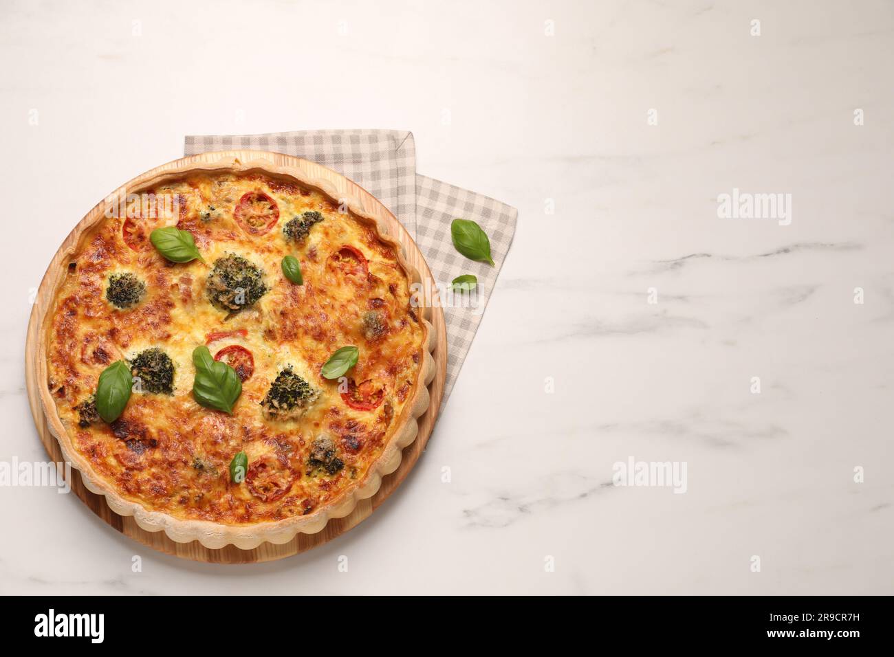 Delicious homemade vegetable quiche and basil leaves on white marble ...