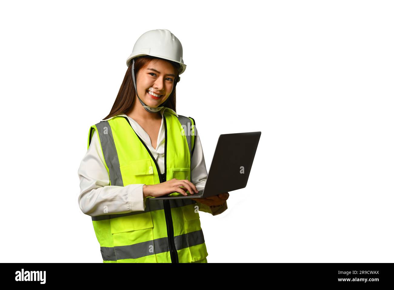 Smiling civil engineer woman wearing helmet and vest holding laptop ...
