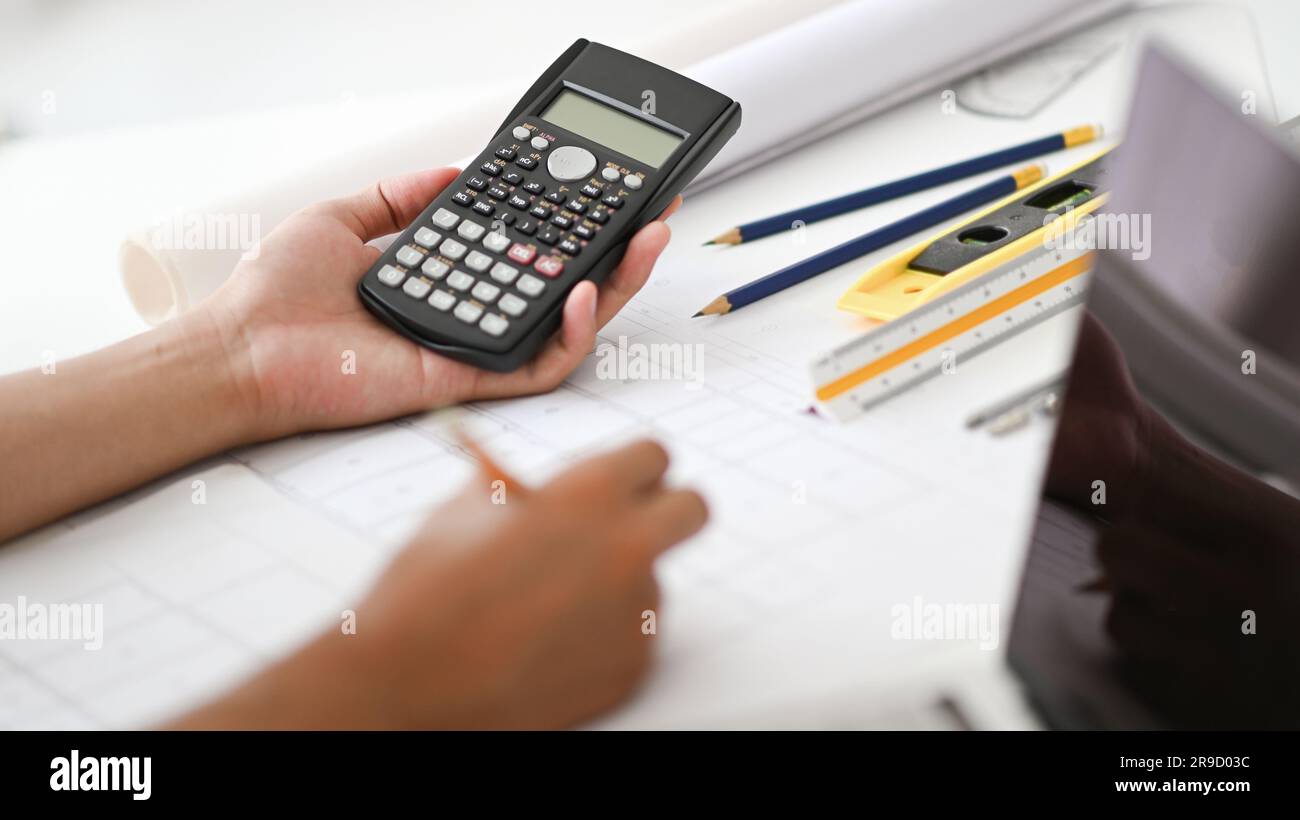 A close-up image of a hand holding a black calculator, positioned to ...