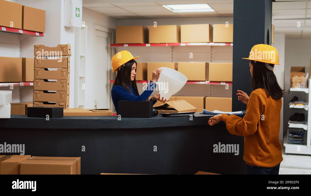Asian team of employees doing supplies quality control in storage room ...