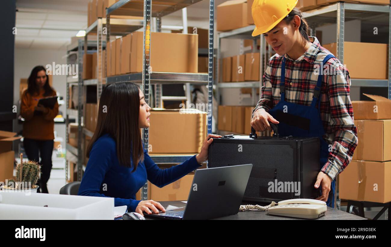 Business owner working on stock logistics with employee in storage room ...