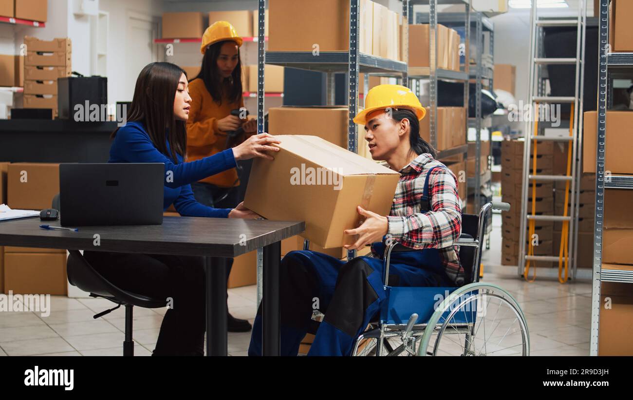 Man in wheelchair working in storage room with goods, employee with ...