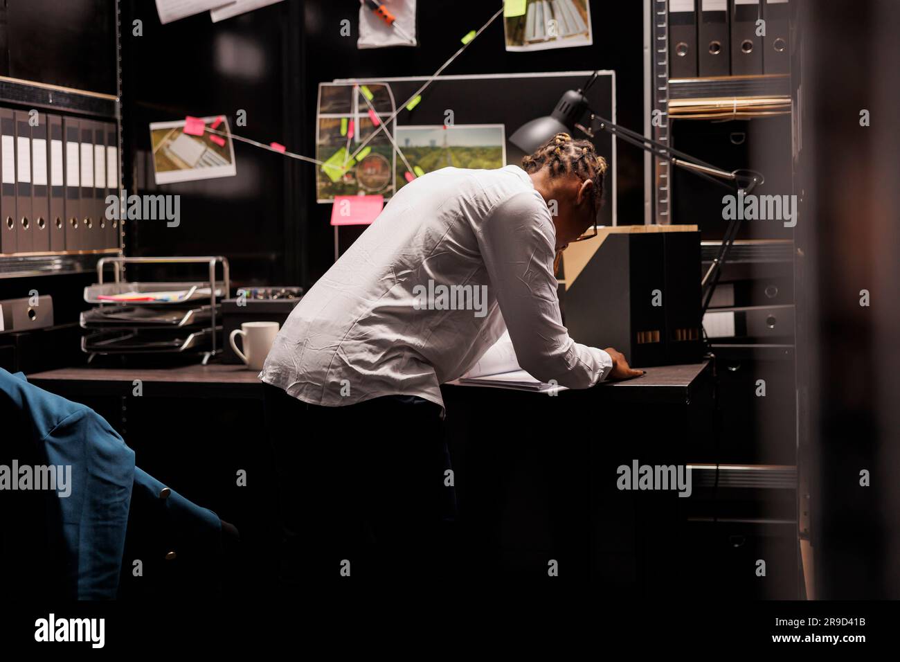African american woman standing near detective desk and reading crime ...
