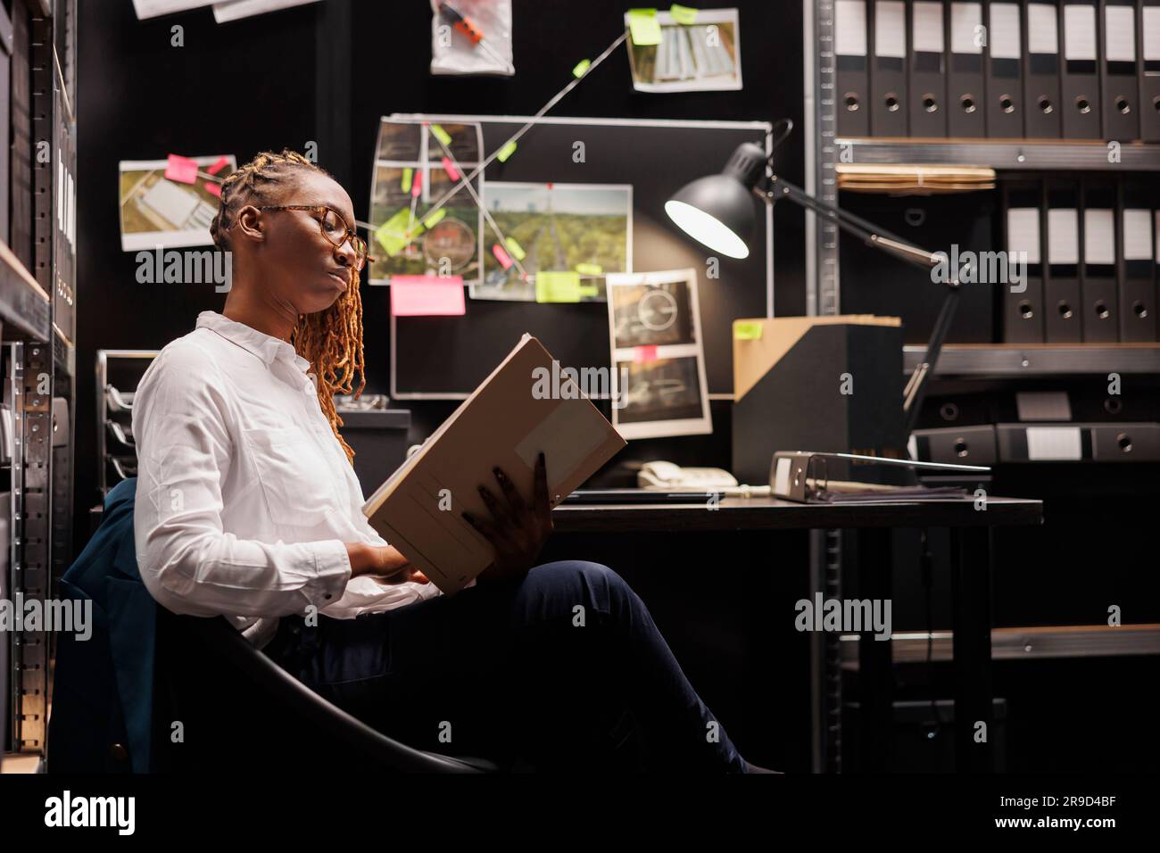 Woman detective analyzing evidence and reading crime case file in ...