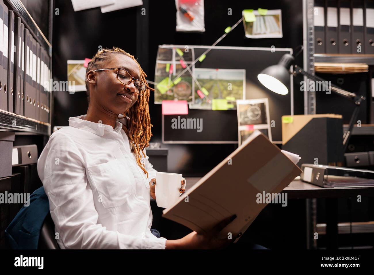 Policewoman reading investigation report while drinking coffee in ...