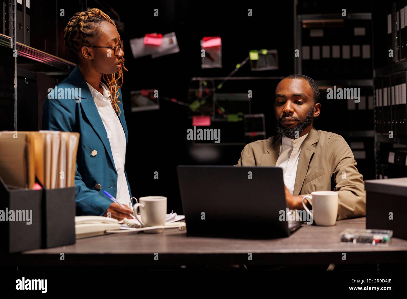 Police detective and secretary working late in office, brainstorming ...