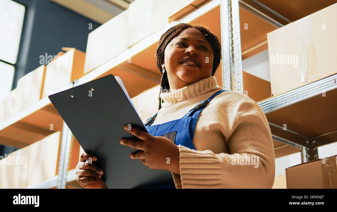 Female worker checking list of papers for inventory, working on stock ...