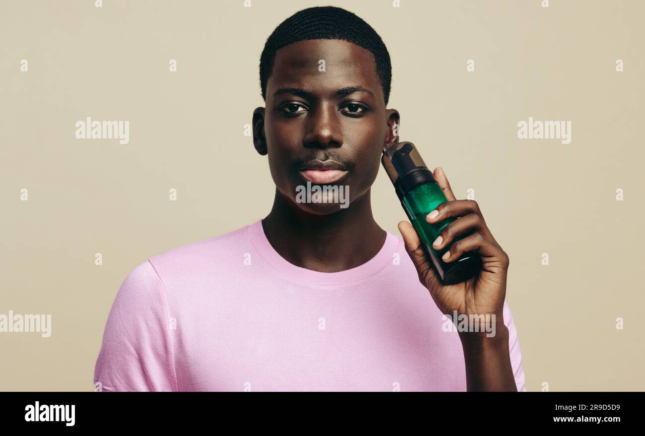 Portrait of a young black man with melanin skin holding a face wash ...