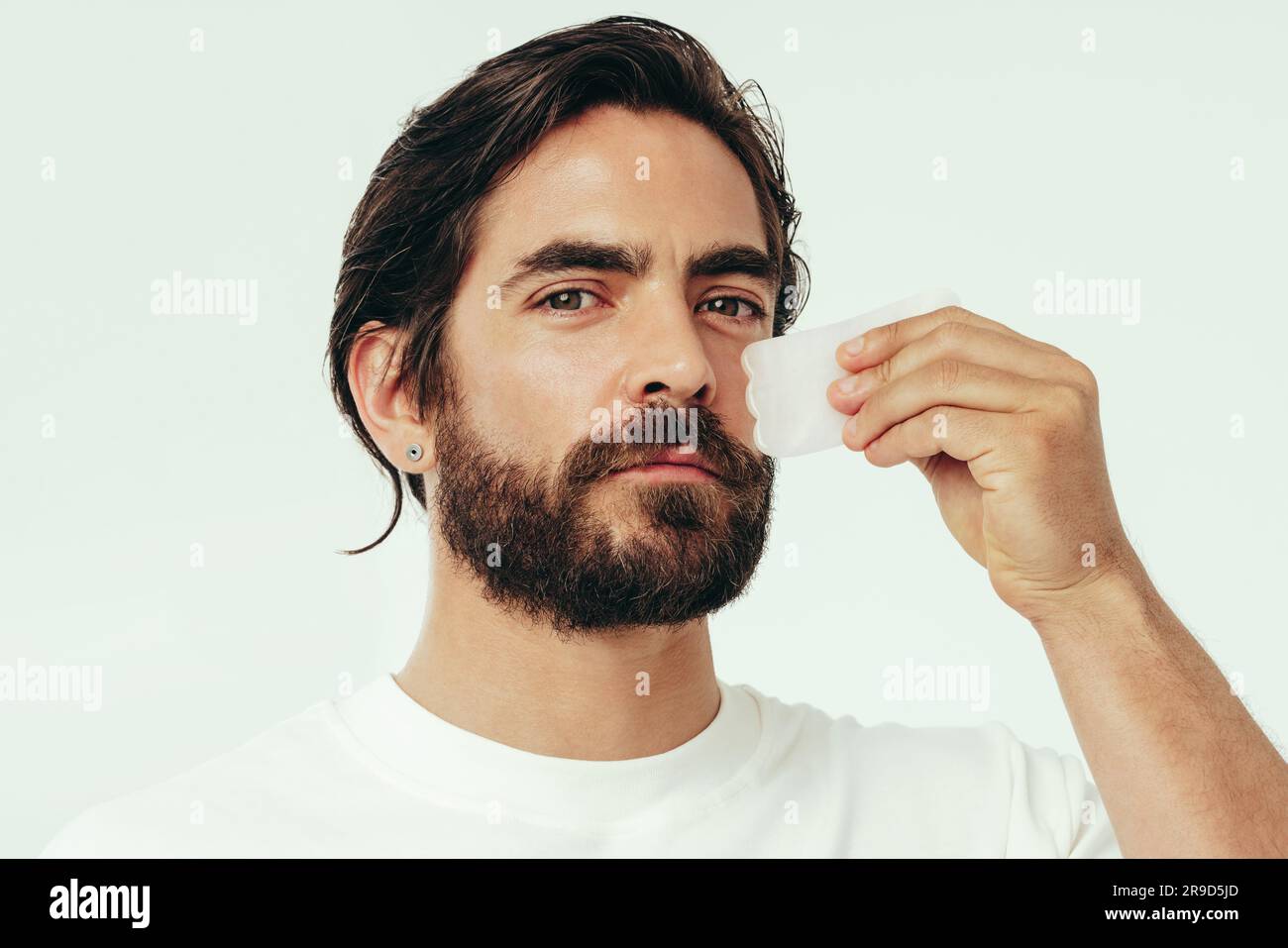 Young caucasian man gently massaging his face with a gua sha stone in a ...