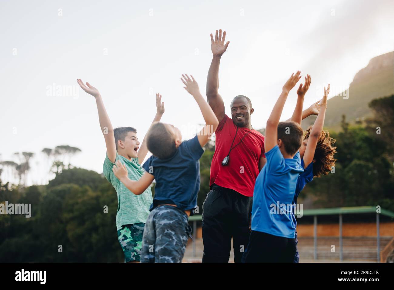 school coach and his team celebrating with raised arms in a field ...