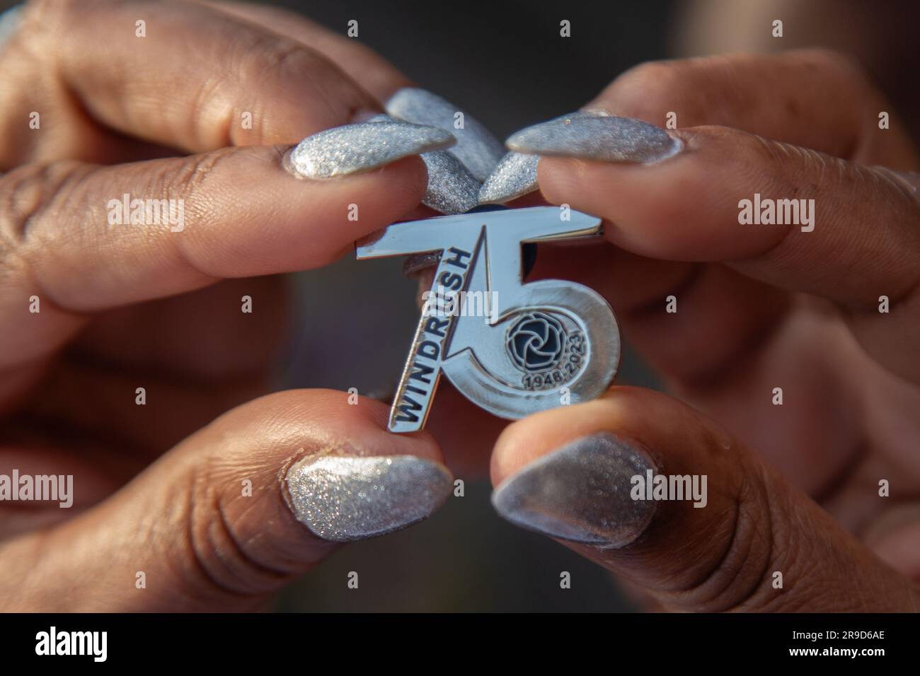 London, UK. 24th June, 2023. A woman holds a 75th Windrush Generation ...
