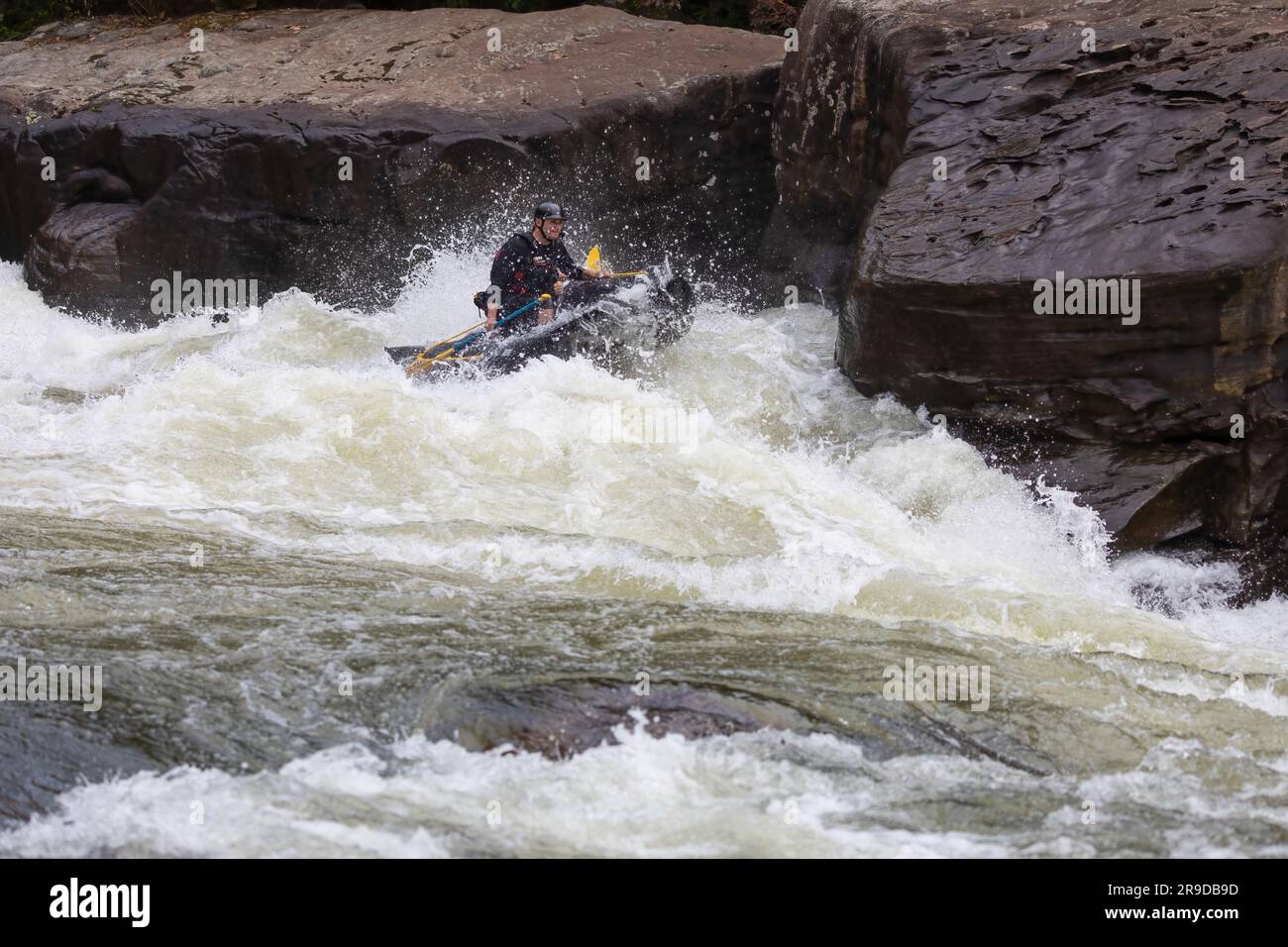 The people in an inflatable boat riding a rushing river's wave. Rafting ...