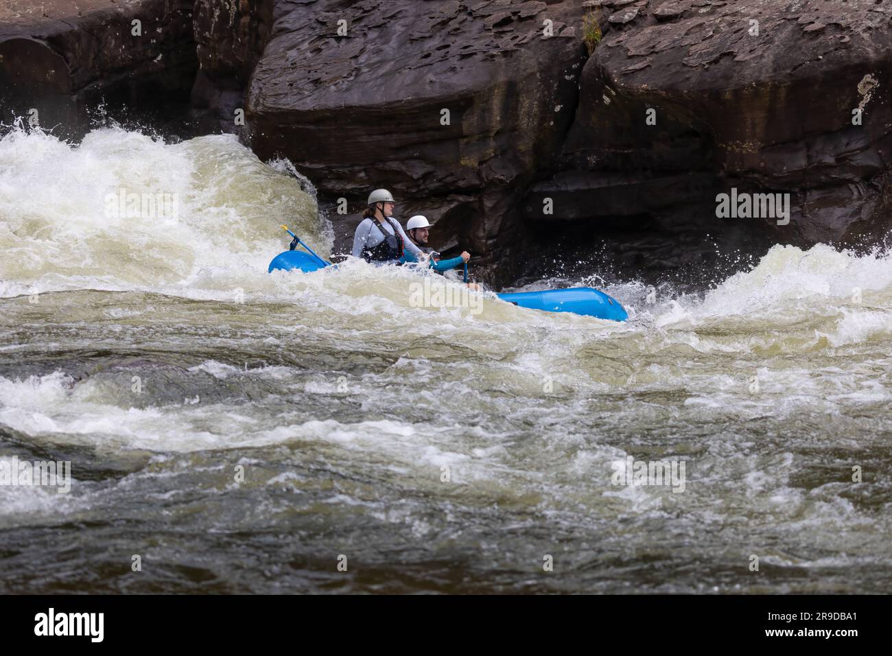 The people in an inflatable boat riding a rushing river's wave. Rafting ...