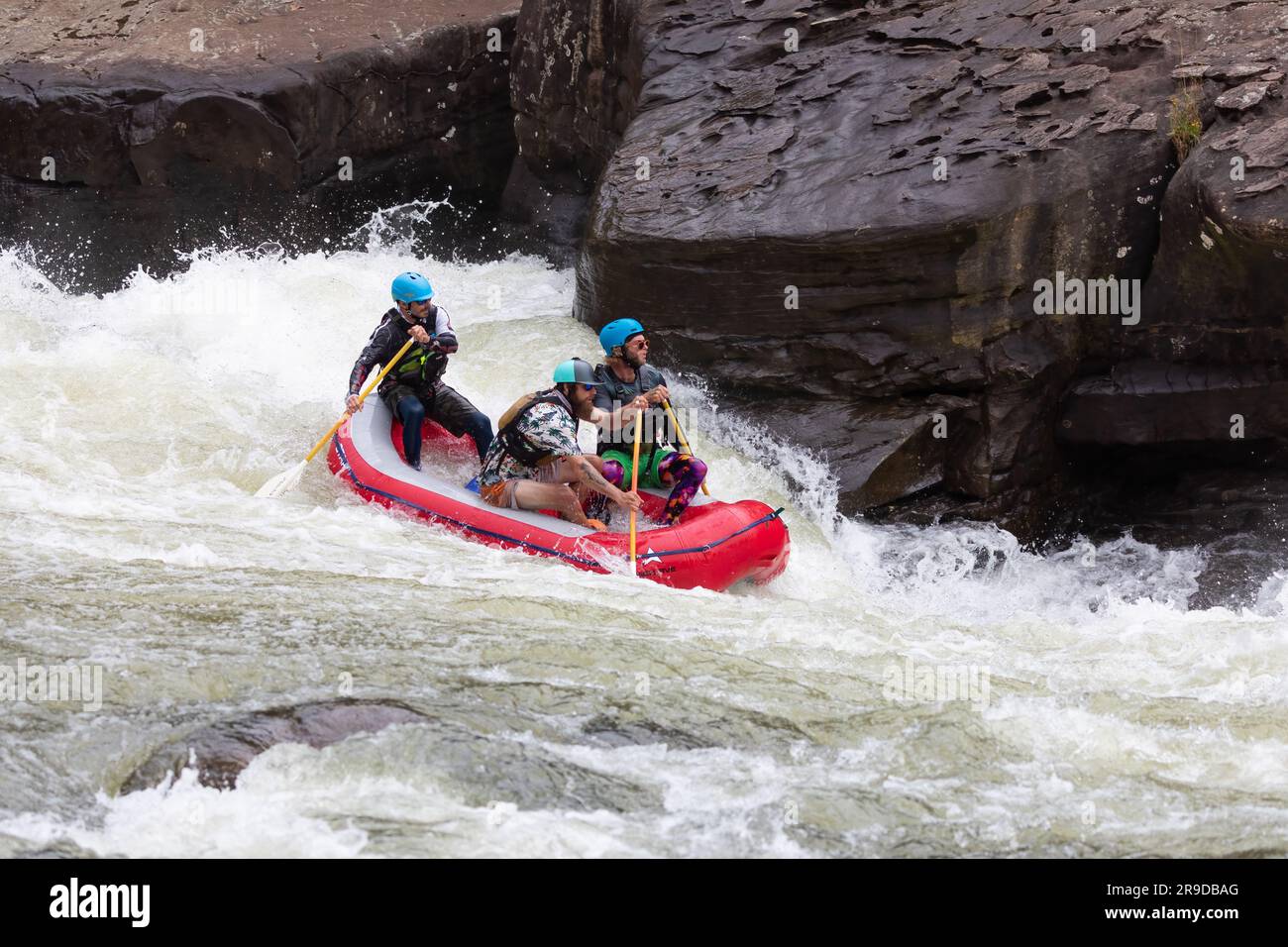 The people in an inflatable boat riding a rushing river's wave. Rafting ...