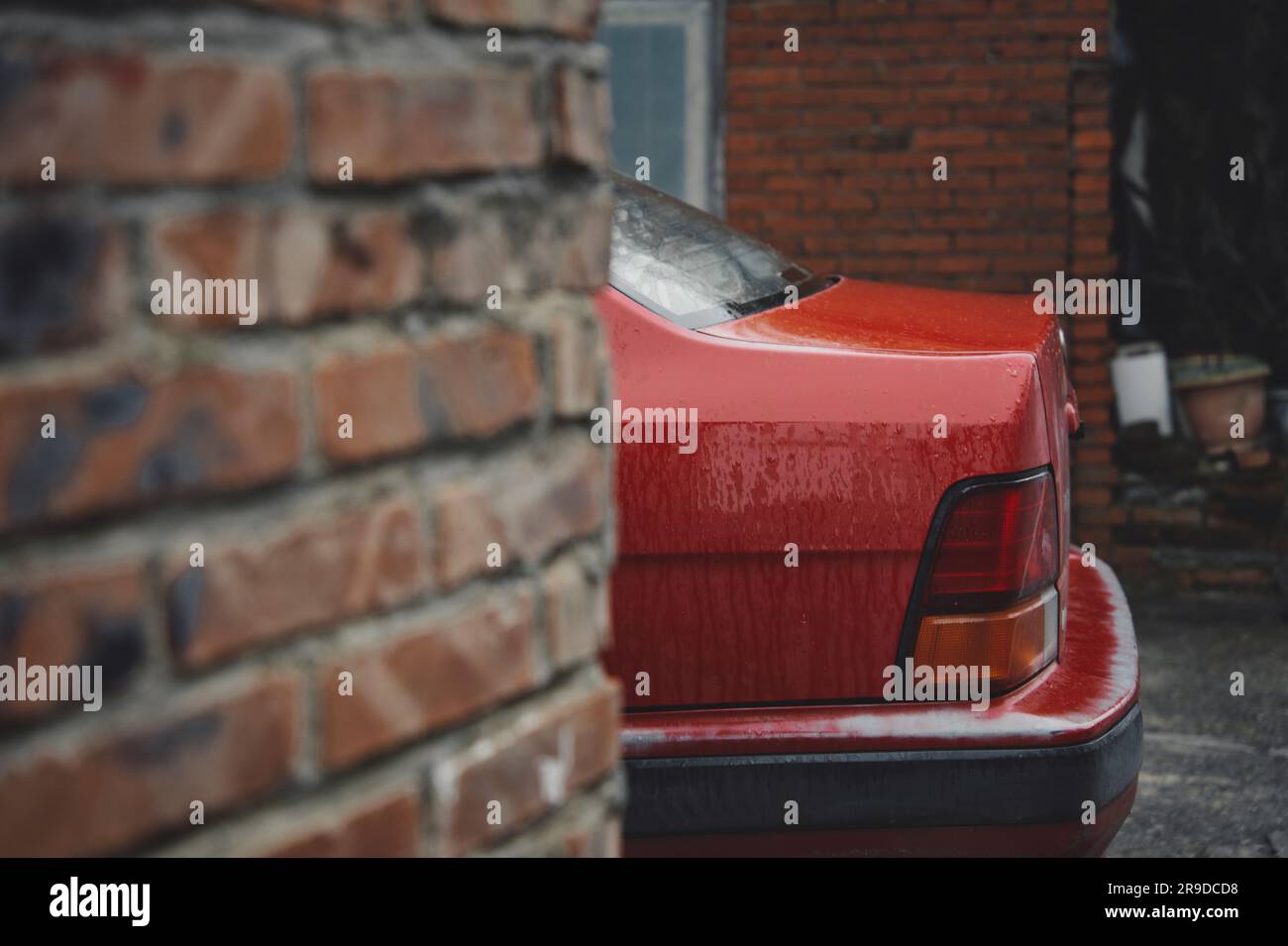 A close-up shot of a vibrant red car parked inside a classic brick ...