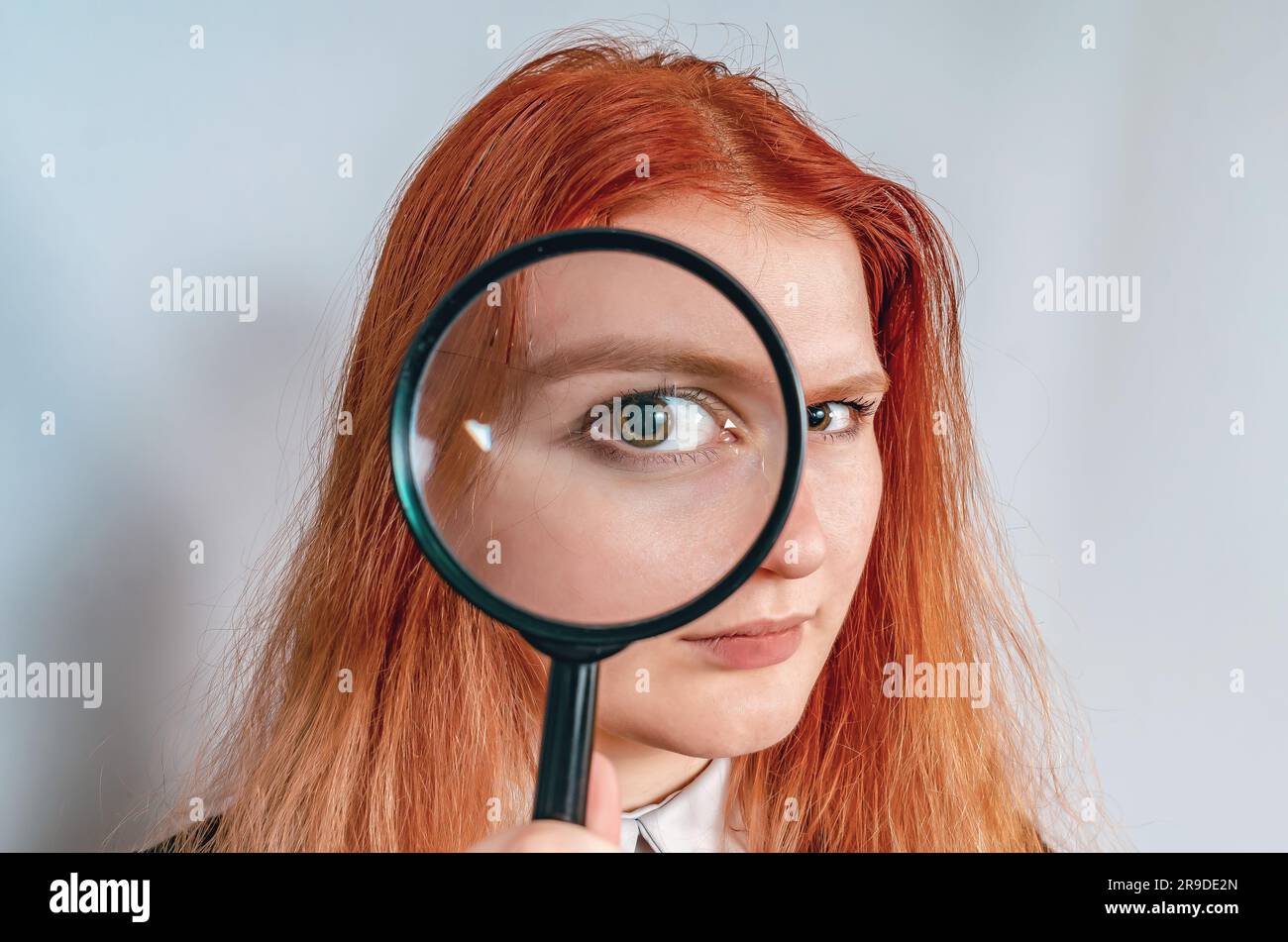 Magnifying glass. Woman's face through magnifying glass. Big eyes ...