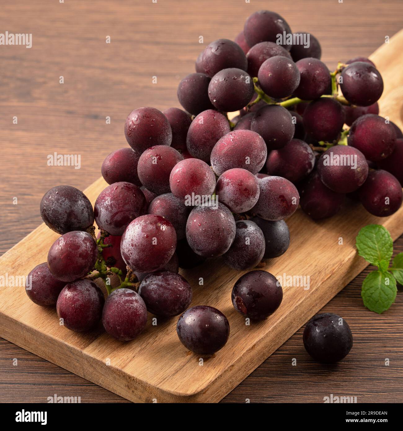 Delicious bunch of purple grapes fruit on a tray over wooden table ...