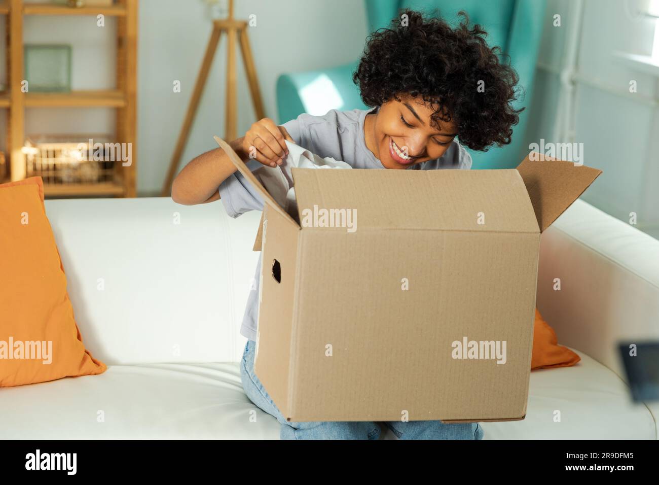 African girl unpacking delivery looking in box. Happy woman opening ...