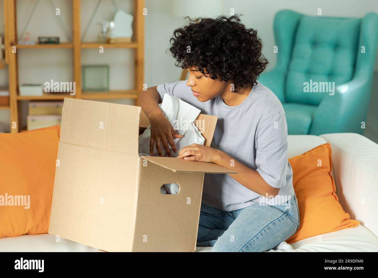 African girl unpacking delivery looking in box. Happy woman opening ...