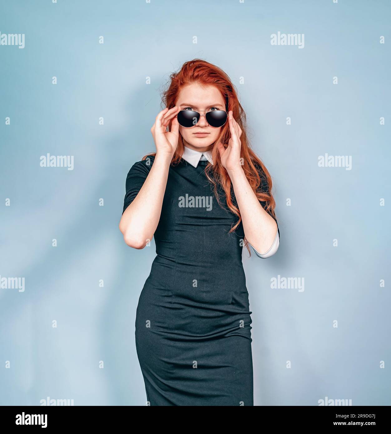 Stylish woman holds black glasses with hands. Black strict dress with a ...