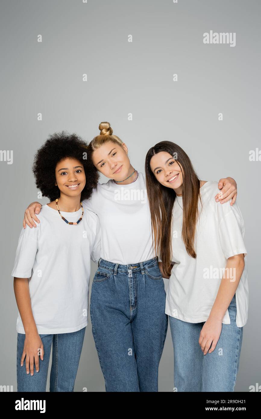 Stylish and cheerful interracial teenage girls in white t-shirts and ...