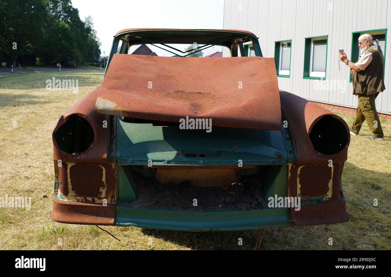 Front of a totally rusted old car with a man in the background ...