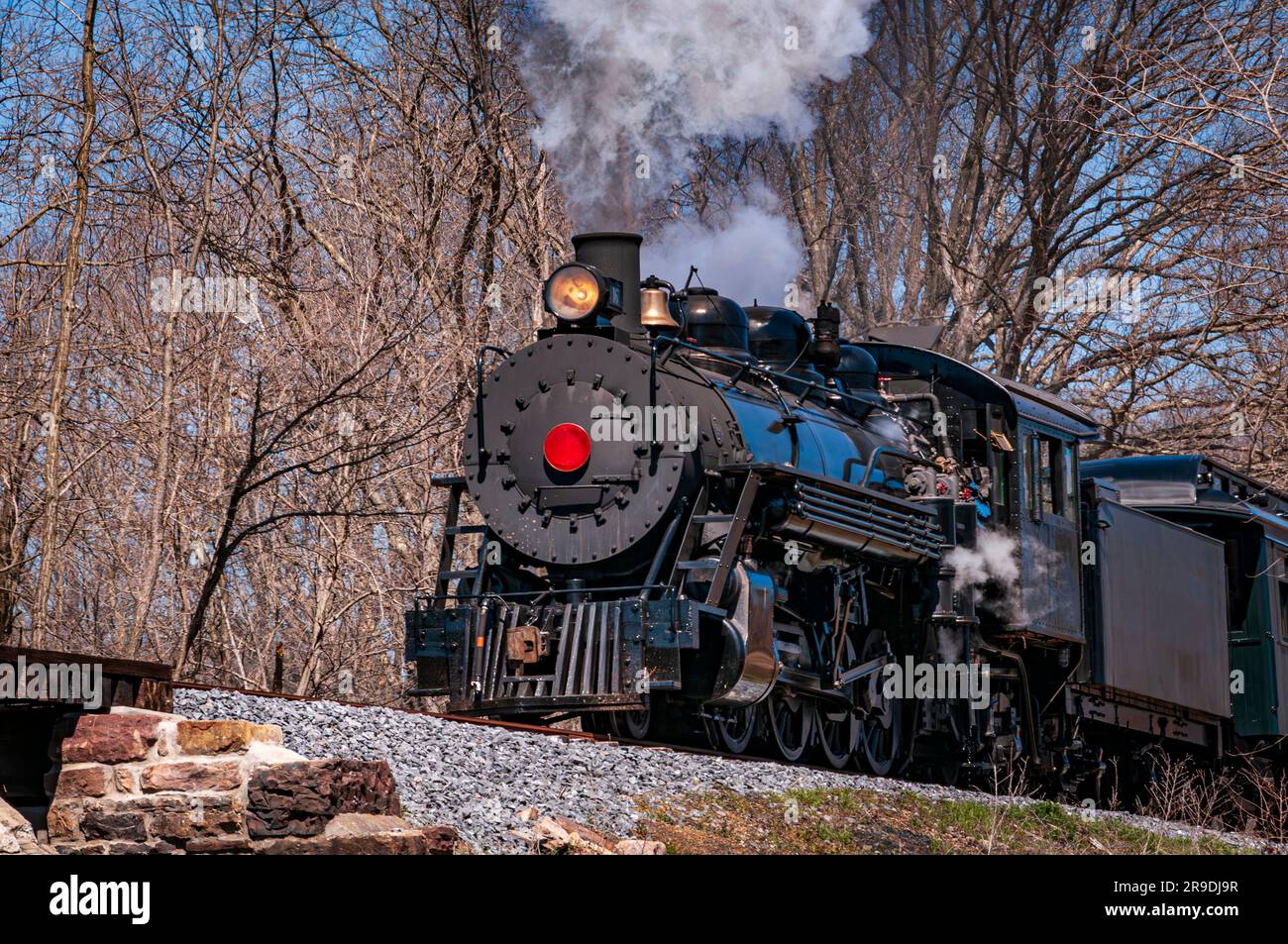 A restored steam passenger train moving slowly blowing lots of black ...