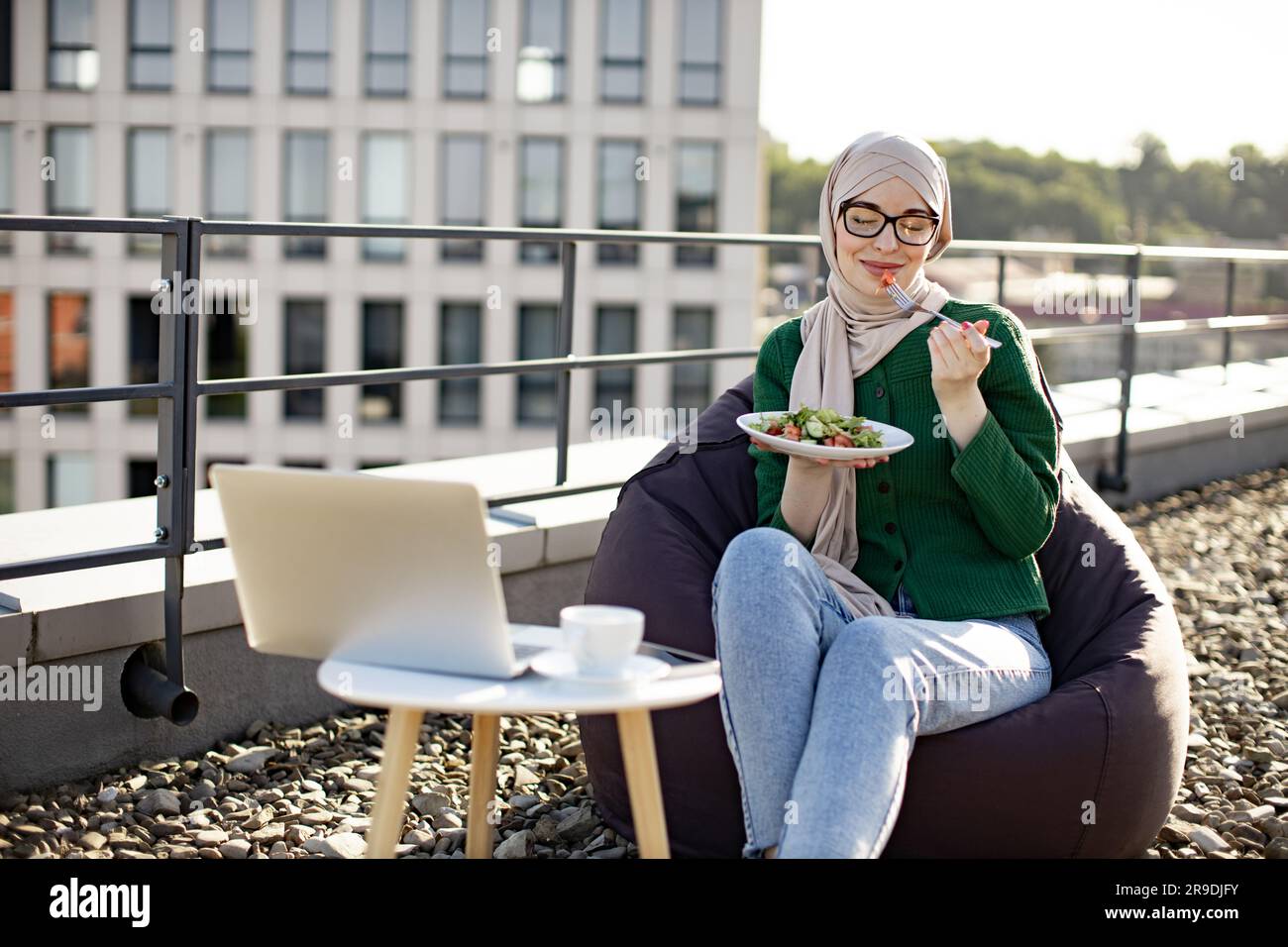 Beautiful female wearing spectacles and hijab tasting crunchy salad ...