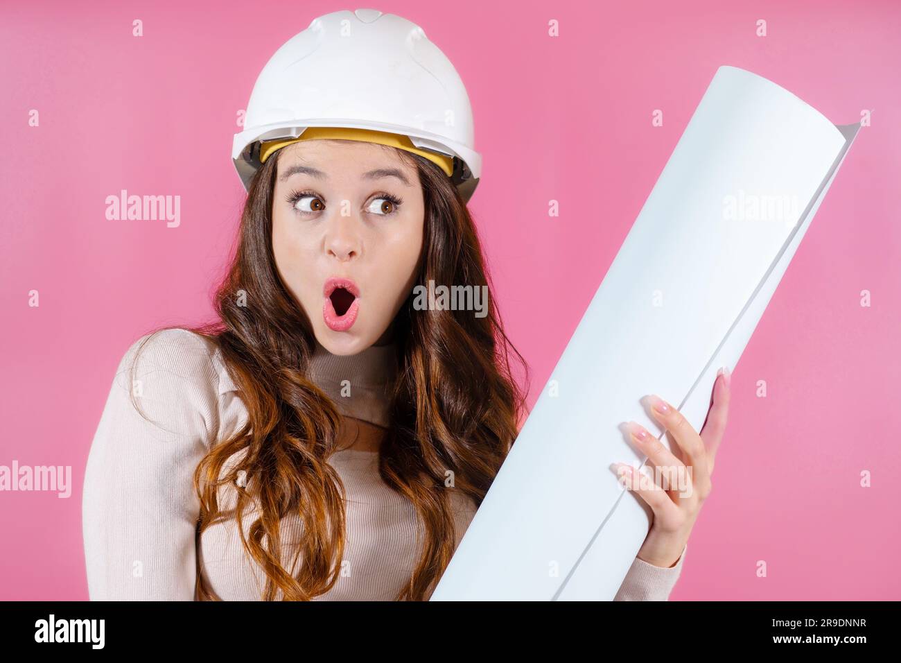 Portrait young woman architect with long hair looking excited holding her project in her hands ...