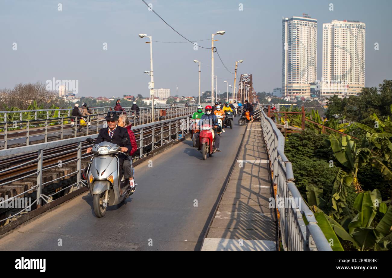 People on motorcycle scooters cross Long Bien Bridge over the Red River ...