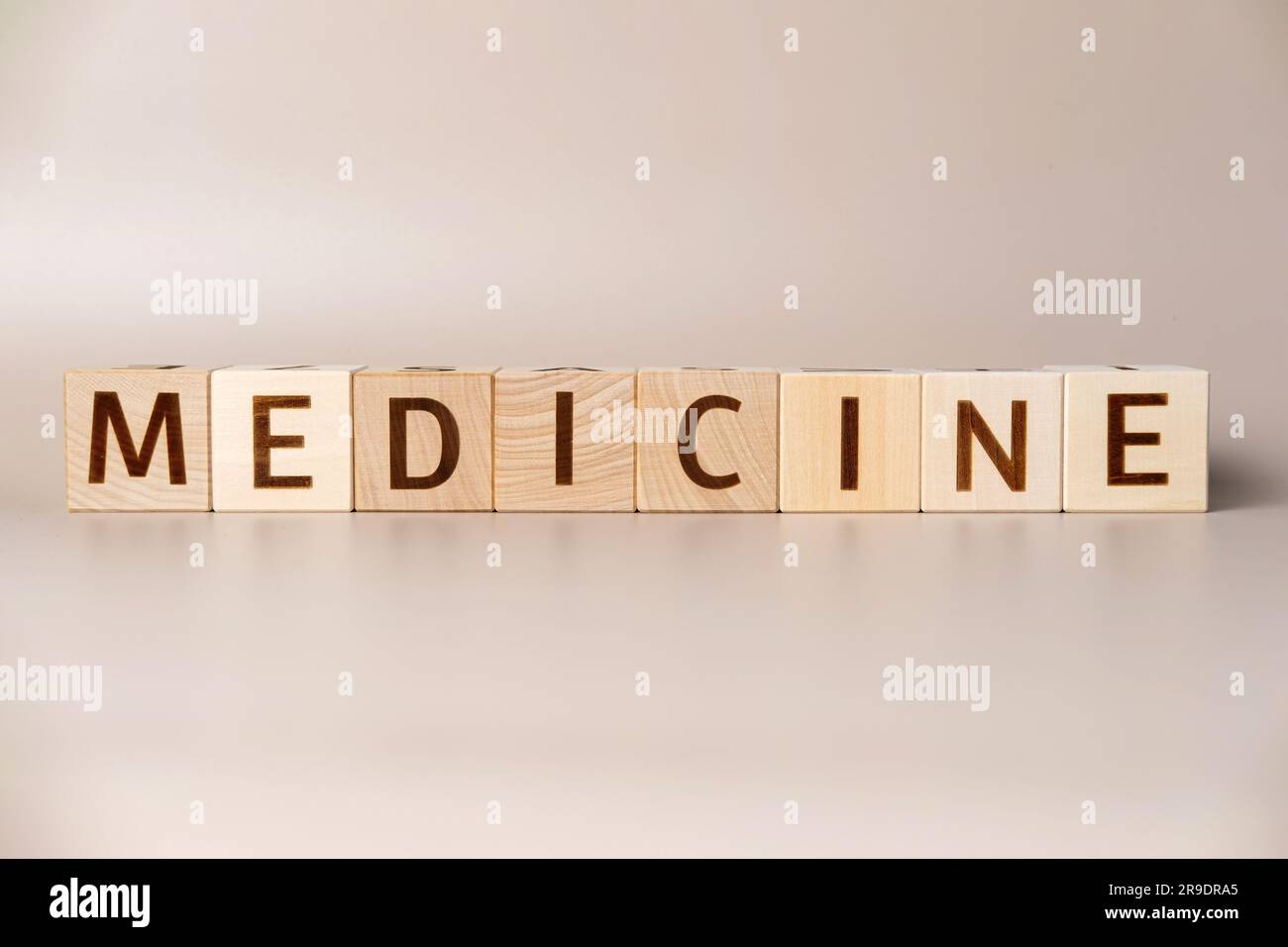 The word MEDICINE on wooden cubes on a beige neutral studio background ...