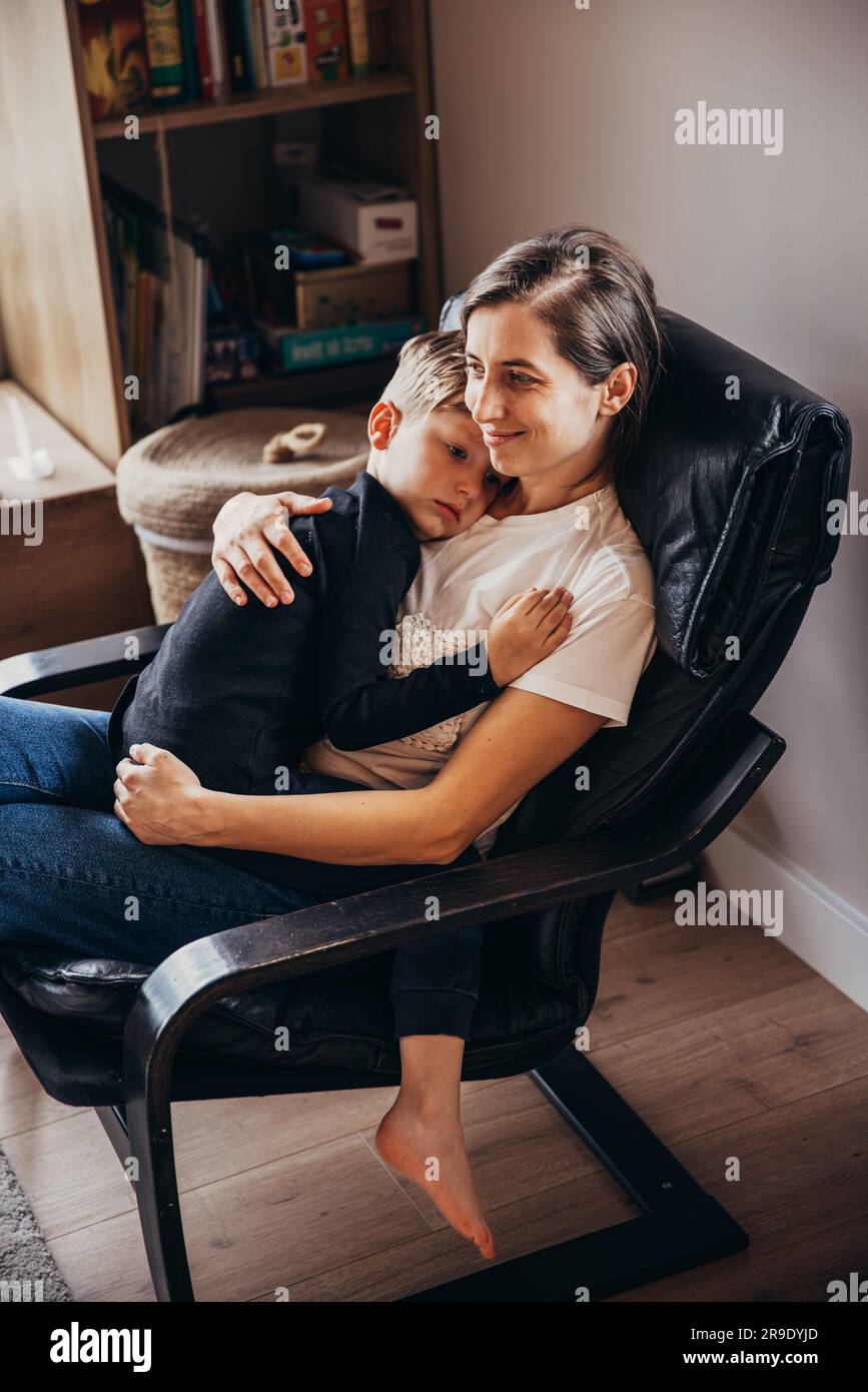 A beautiful mother is comforting her child sitting in a black chiar ...
