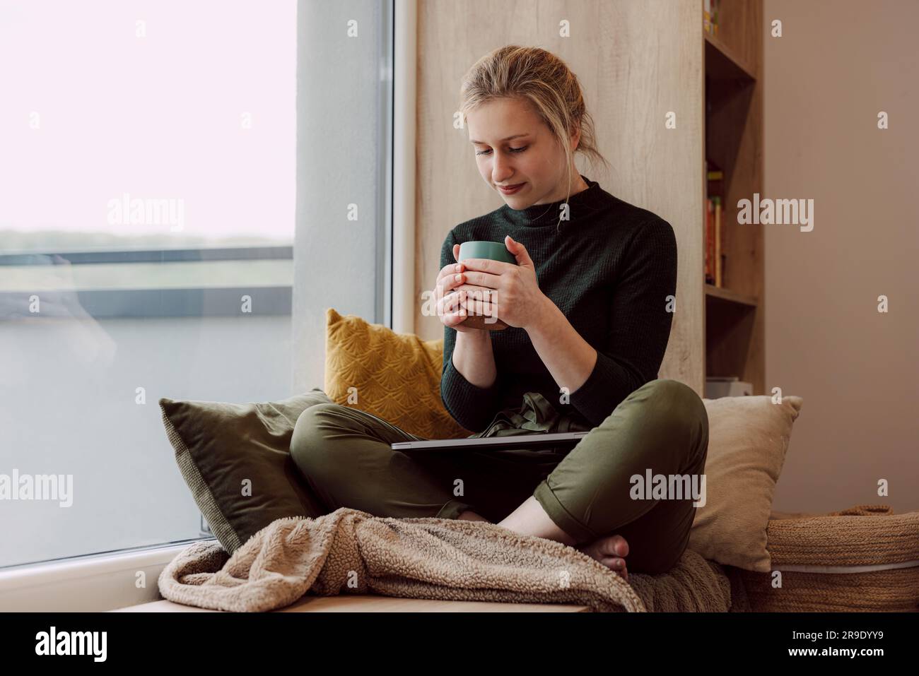 A beautiful woman working remotely trying to balance wellbeing and work ...