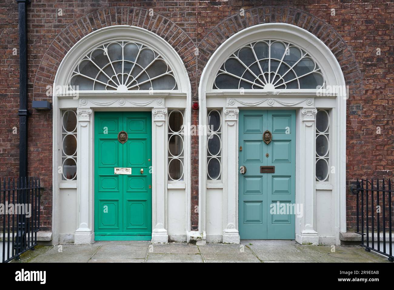 A pair of neighboring Georgian style front doors with ornate fanlight ...