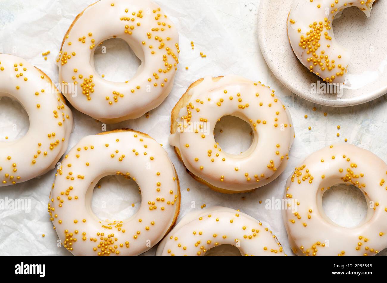 Homemade baked iced donuts with golden pearls on a white plate and on ...