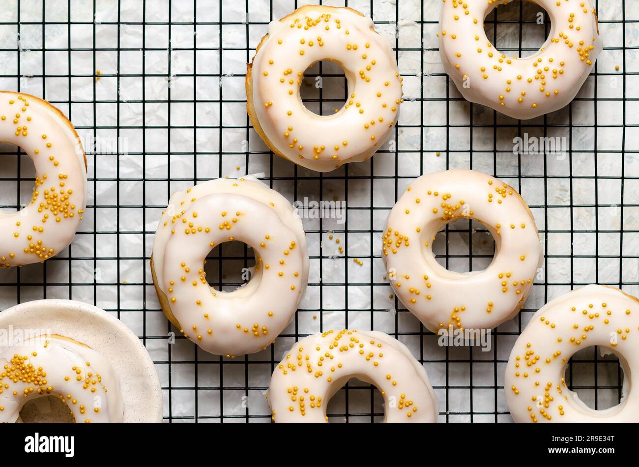Homemade baked iced donuts with golden pearls on a black rack Stock ...