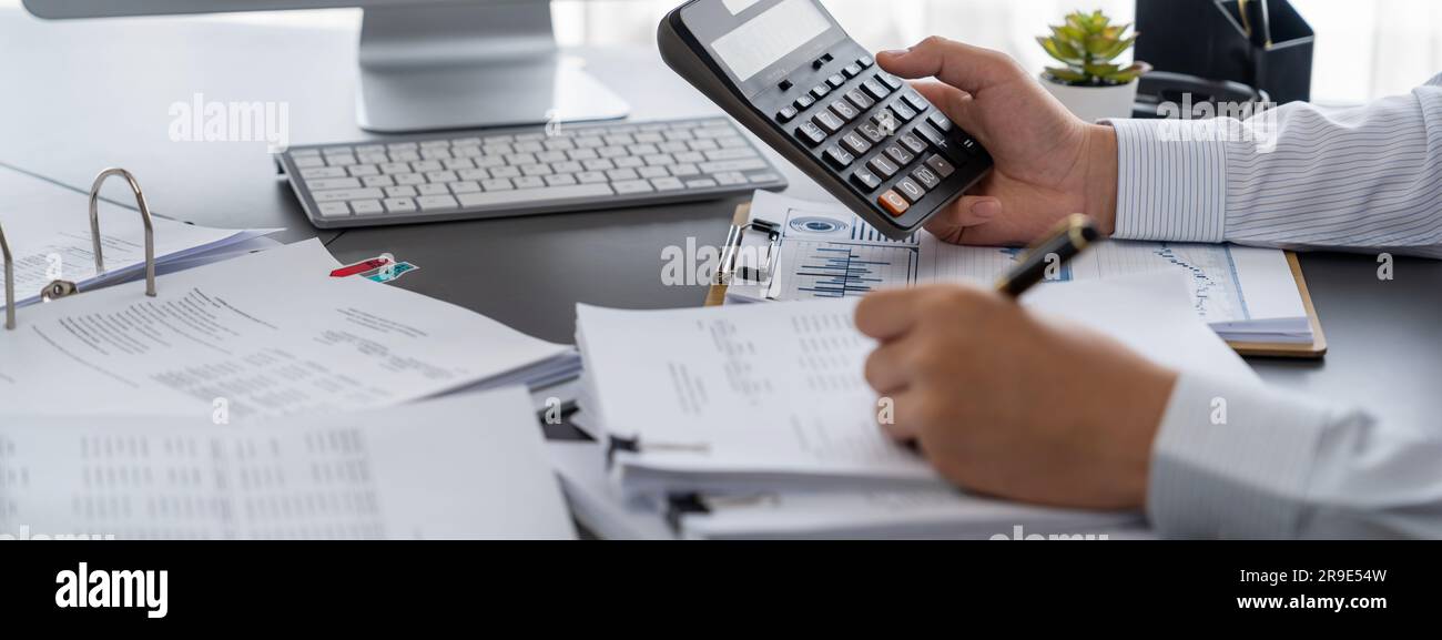 Corporate auditor calculating budget with calculator on his office desk ...