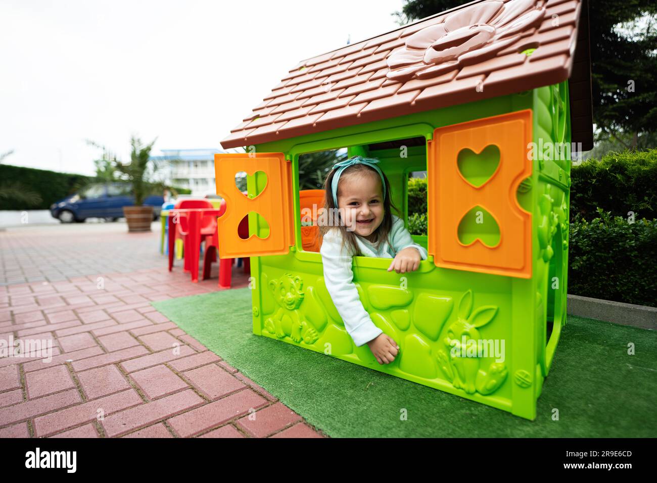Little girl playing in green plastic kid house at children's playground ...