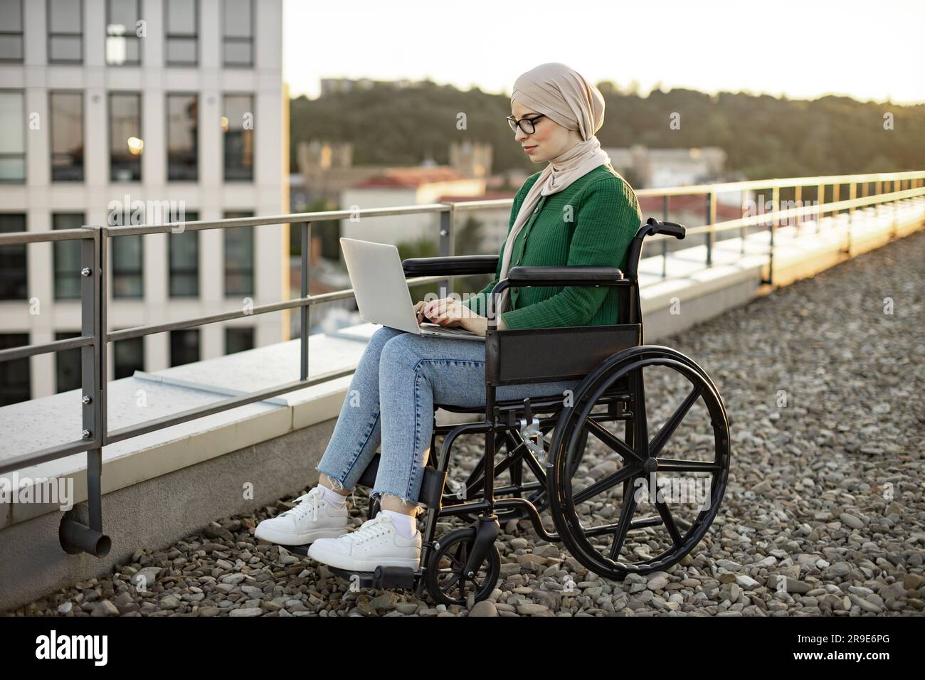 Focused young female with mobility impairment using portable computer ...