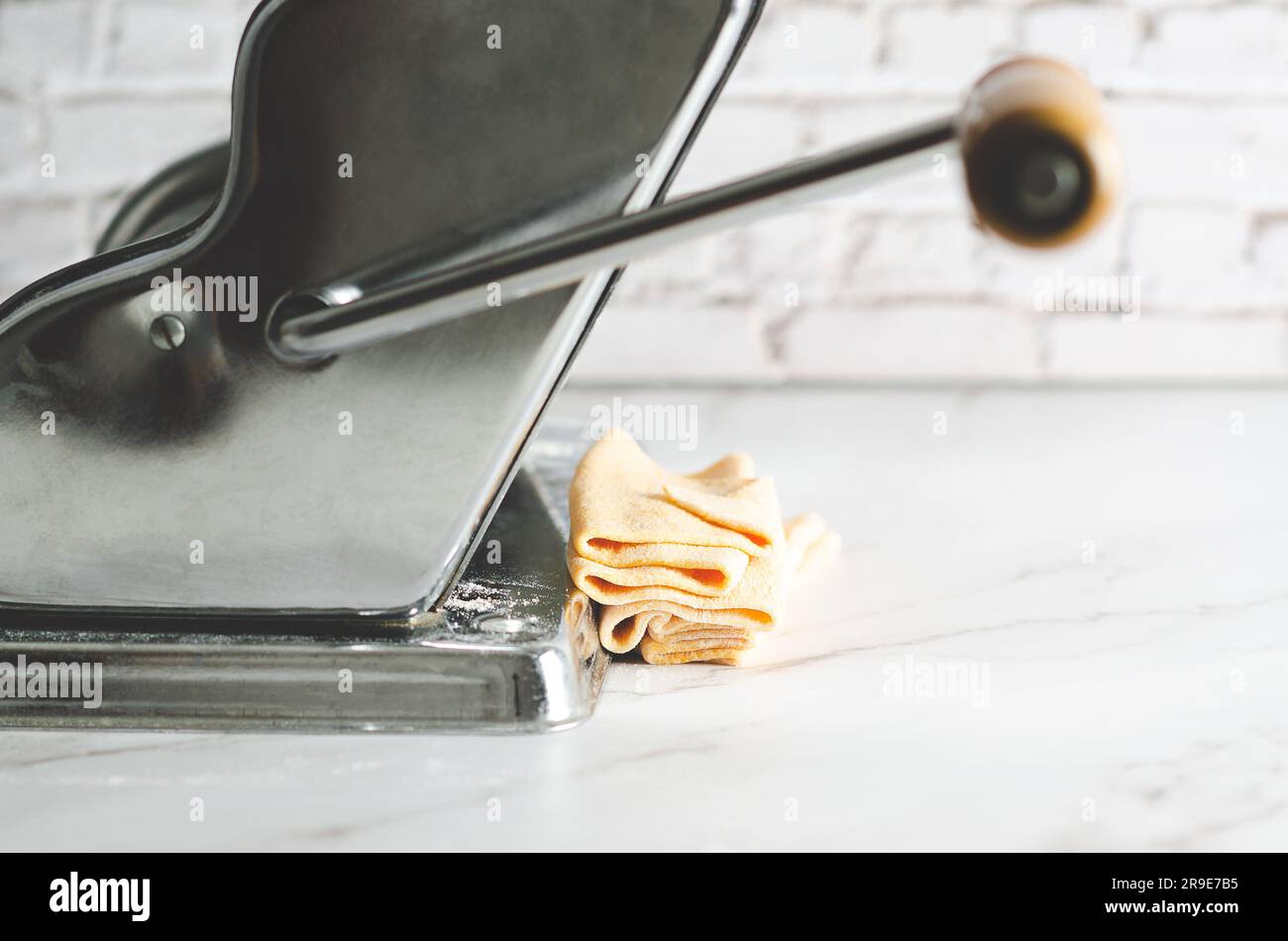 Butternut squash dough in a pasta maker machine on marble background ...
