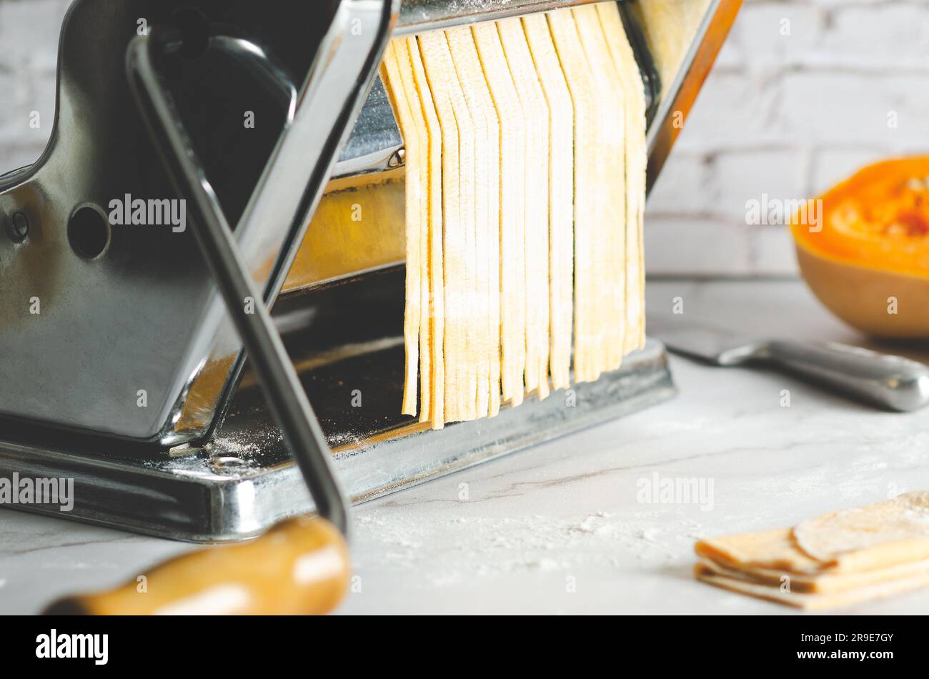 Butternut squash noodles in a pasta maker machine, a knife and a piece ...