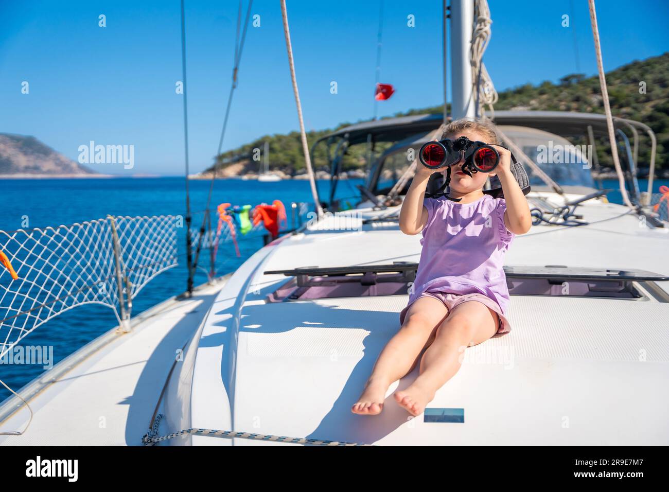 Little girl on a yacht looking through binoculars in the sea Stock ...
