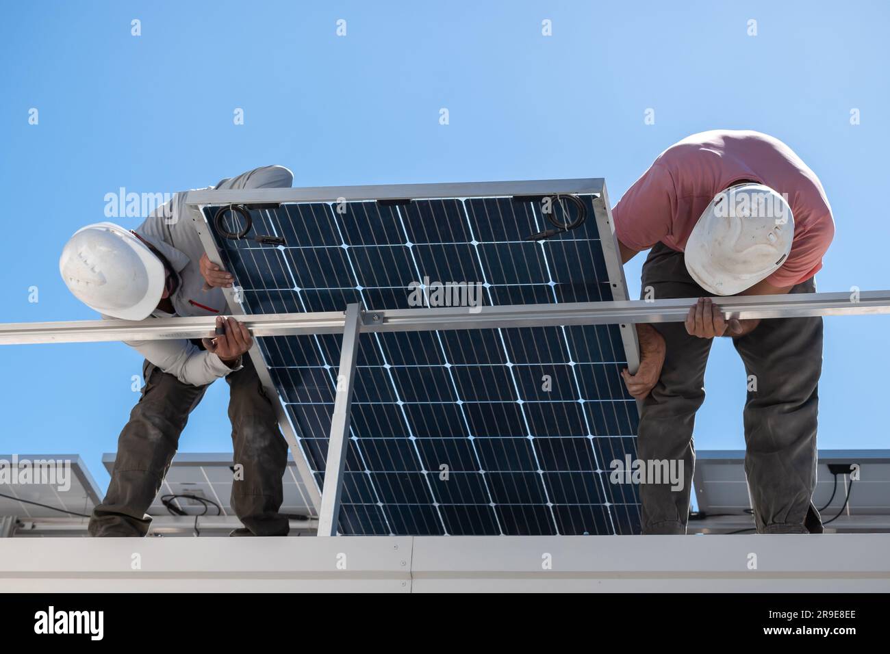 The two men installing a solar panel on the rooftop Stock Photo - Alamy