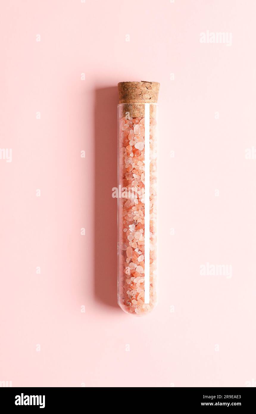 Himalayan pink salt in a glass container with cork on pink background ...