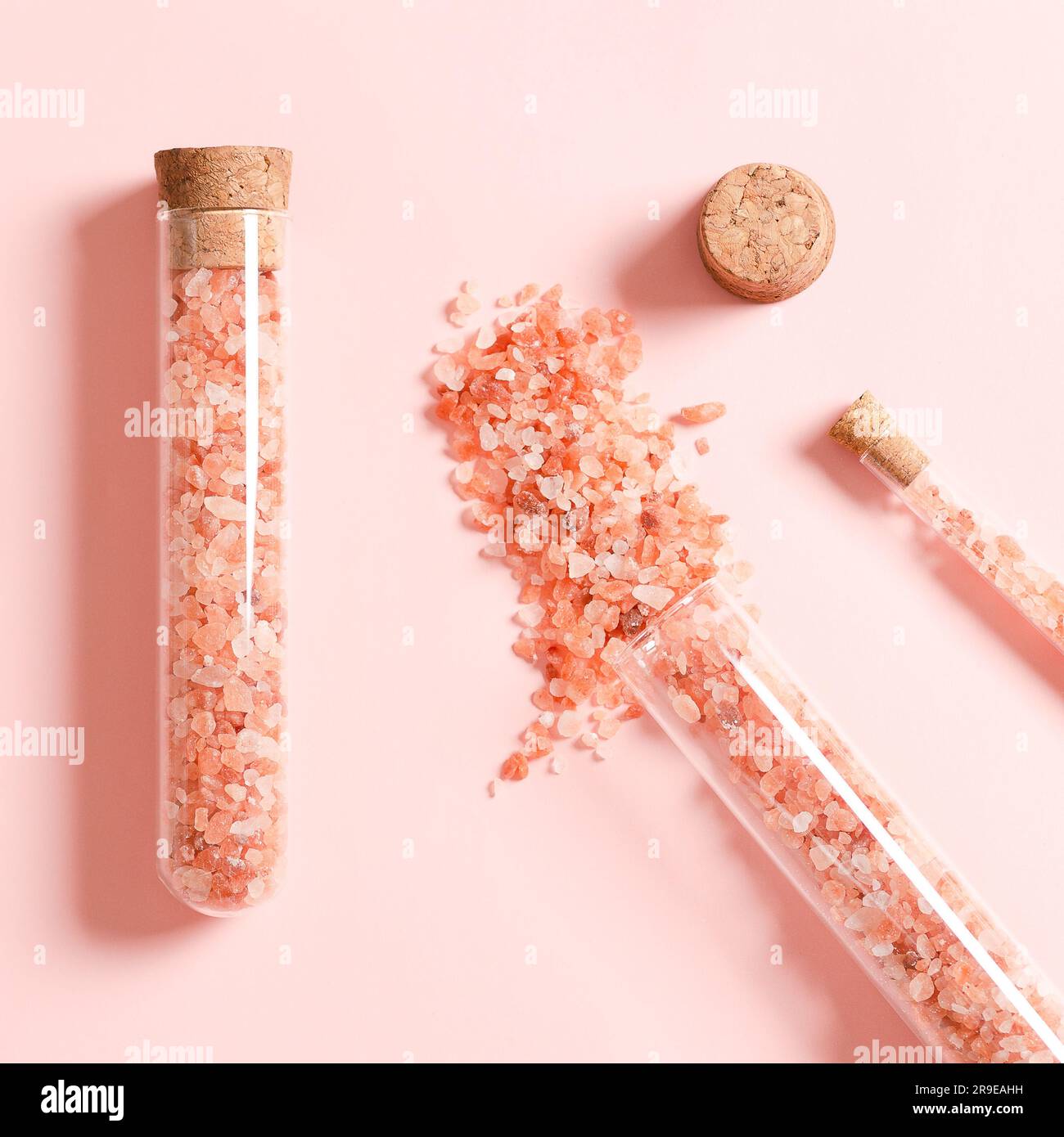 Himalayan pink salt in glass containers with cork on pink background ...