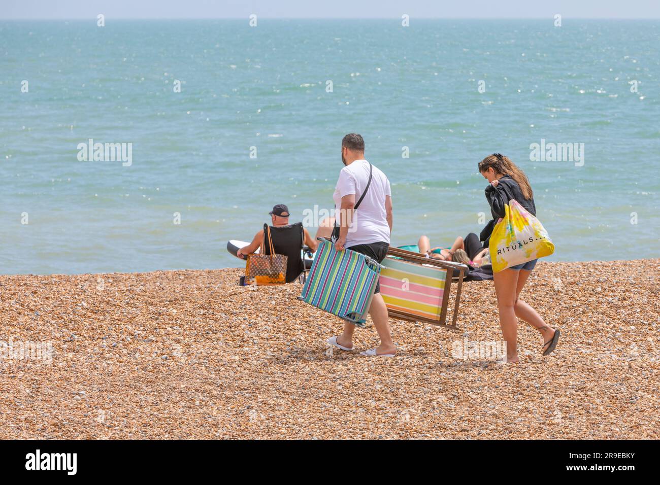 People relaxing and sunbathing on a shingle beach by a calm sea Stock ...