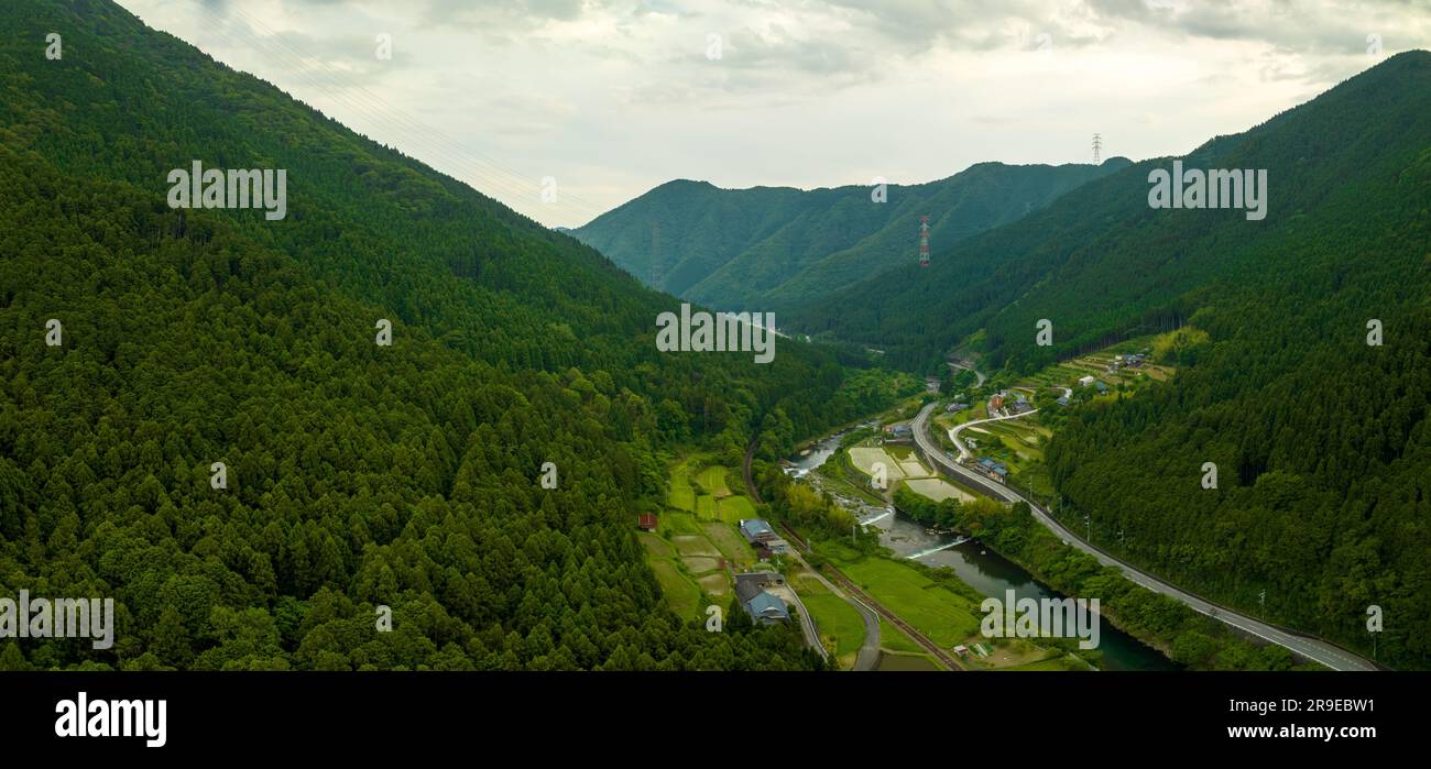 Small farming village in valley between green forested mountains Stock ...