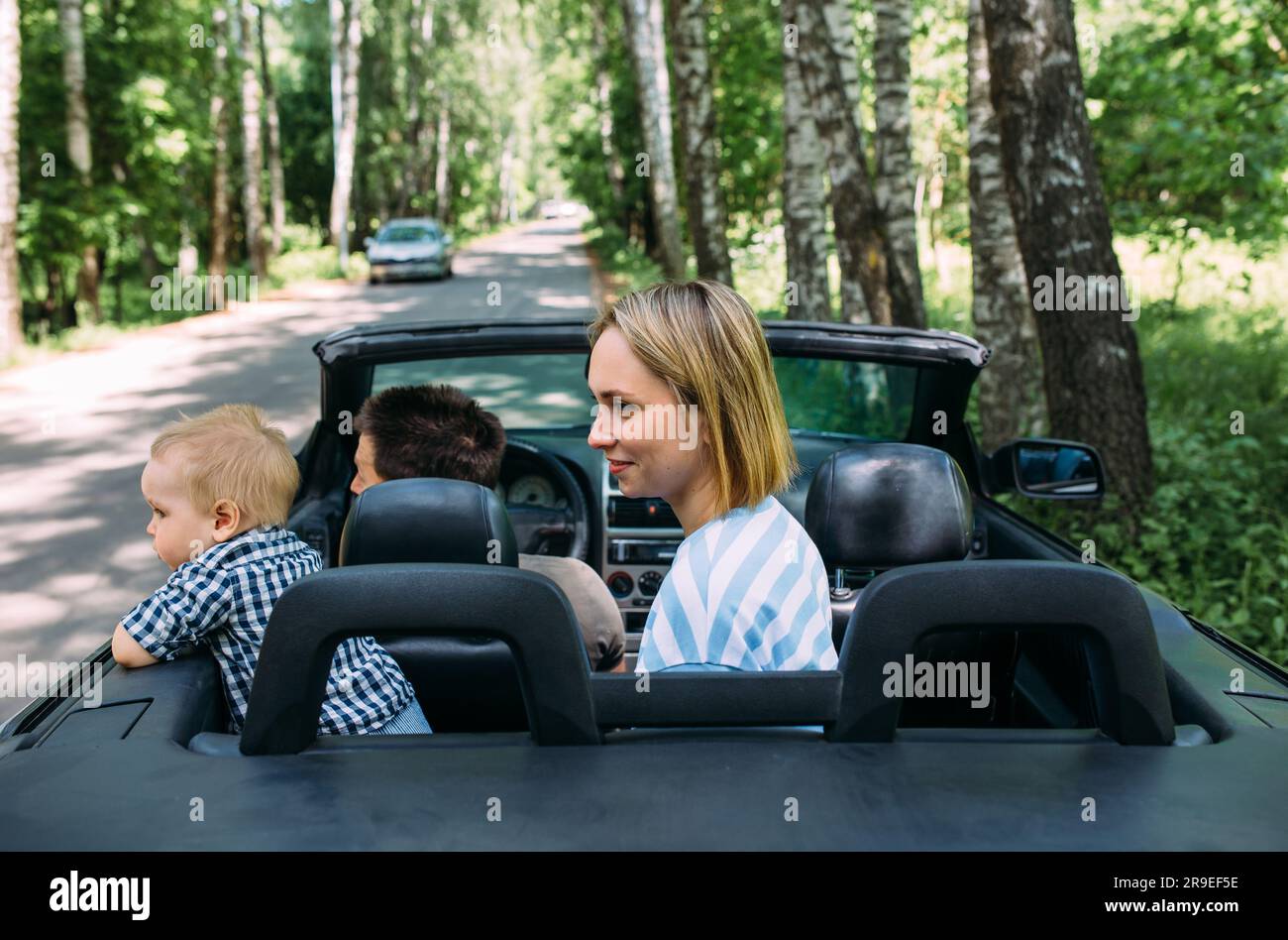 Mom, dad and little son in a convertible car. Summer family road trip ...