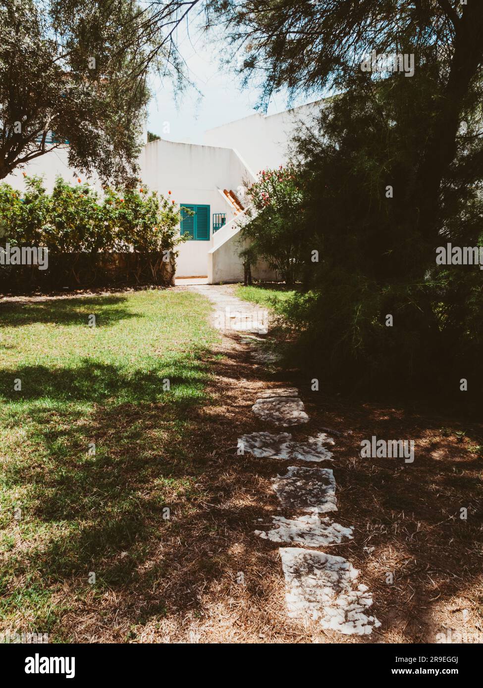 Path in the shade of trees leading to a white apartment building with ...