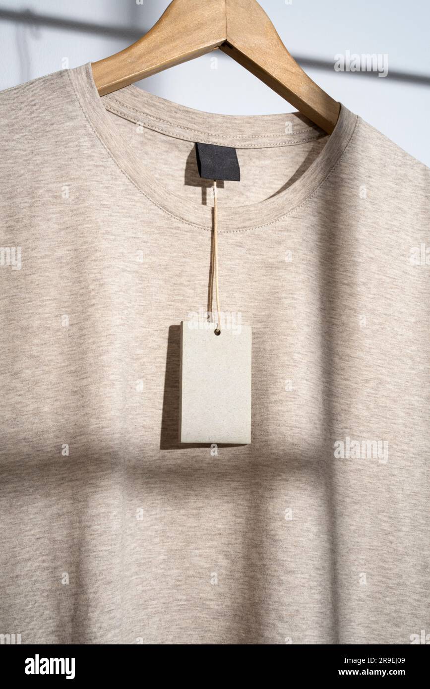 Beige t-shirt with blank price tag mockup, template on wooden hanger ...